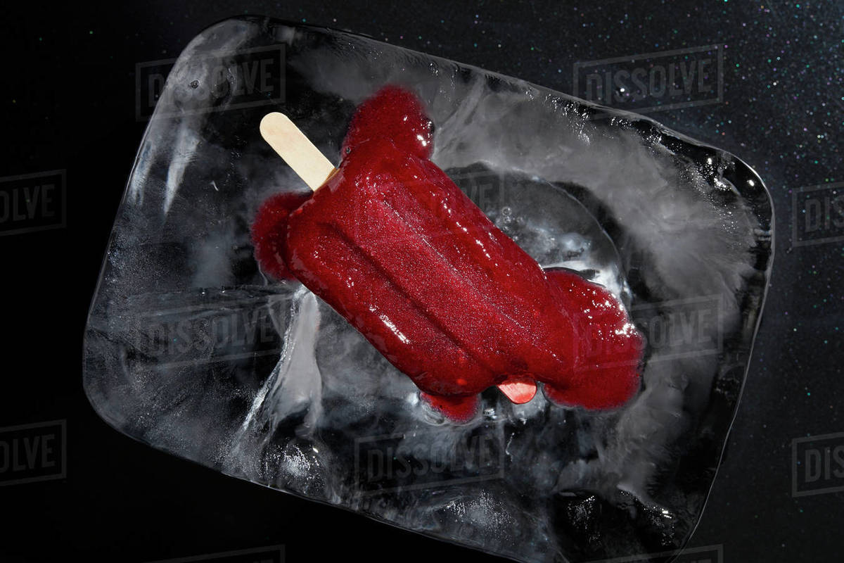 Homemade raspberry iced lolly melting on block of ice, overhead view ...