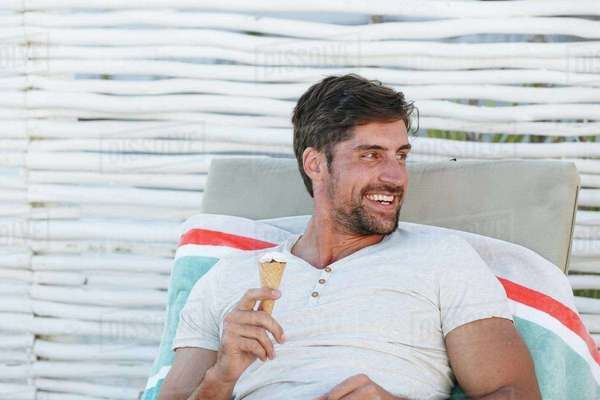 Man enjoying ice cream cone on deckchair - Royalty-free Stock Photo ...