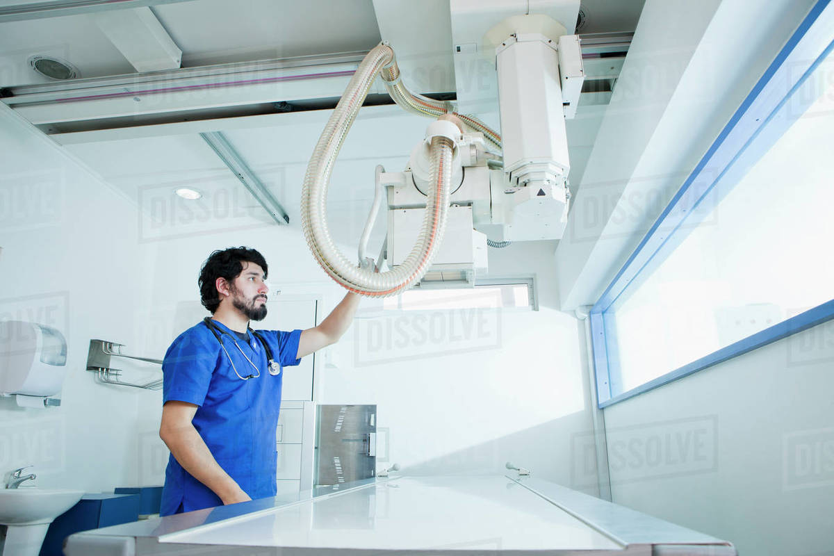 Young male radiographer preparing X-ray machine in radiology department ...
