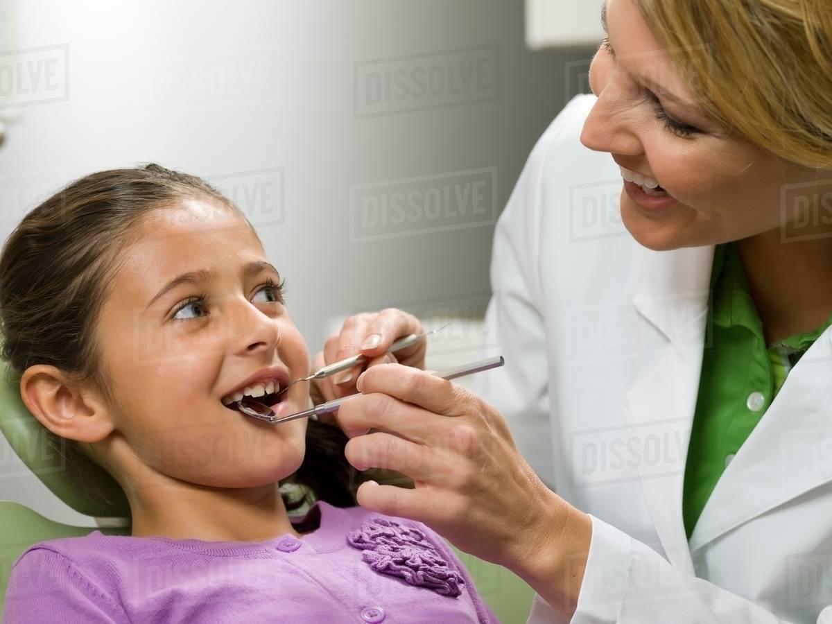 Dentist looking at young girl's teeth - Stock Photo - Dissolve