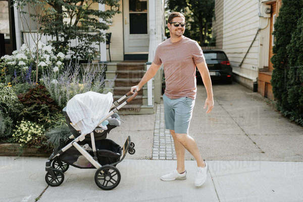 Father pushing baby carriage on pavement - Stock Photo - Dissolve