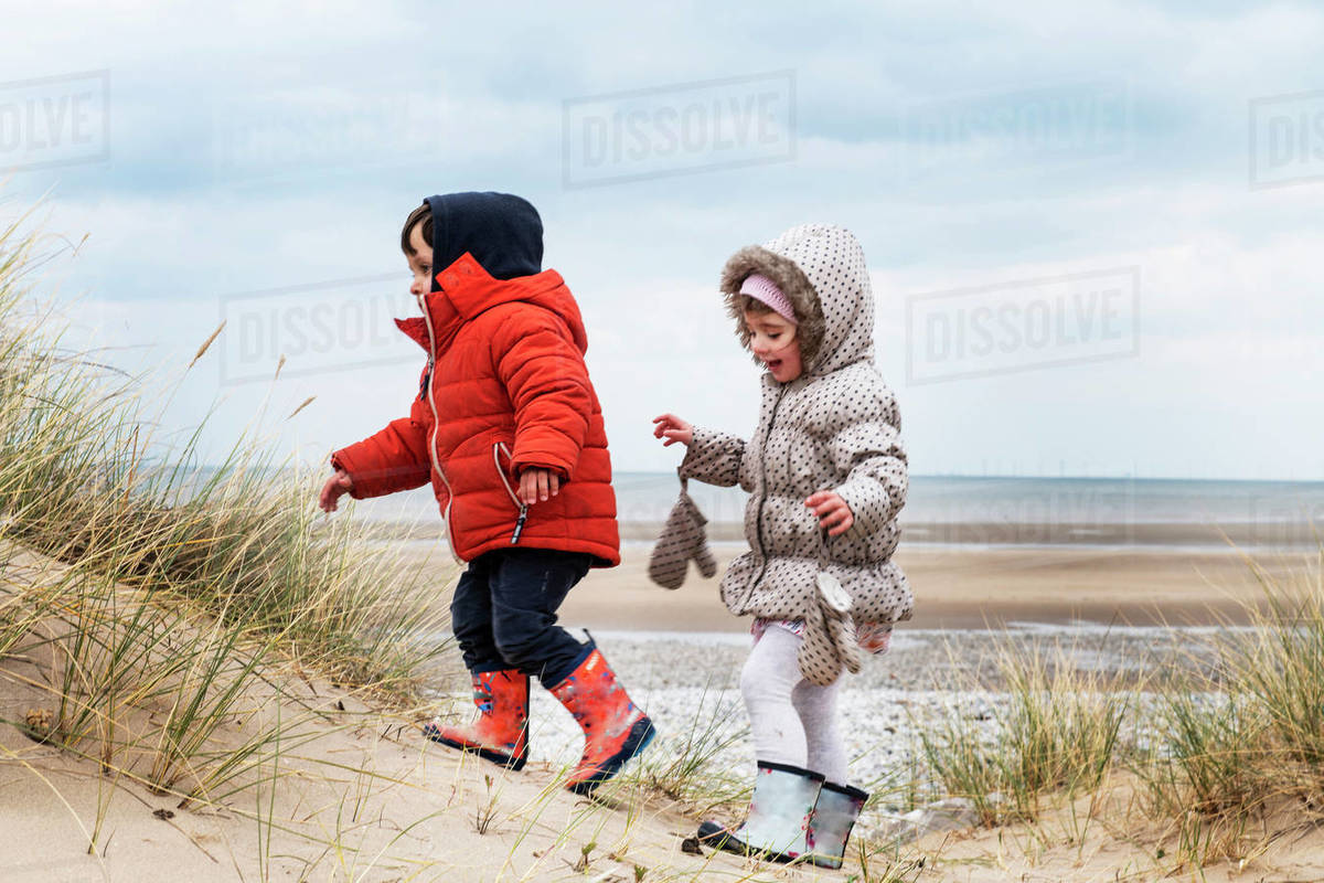 Siblings exploring beach - Royalty-free Stock Photo | Dissolve