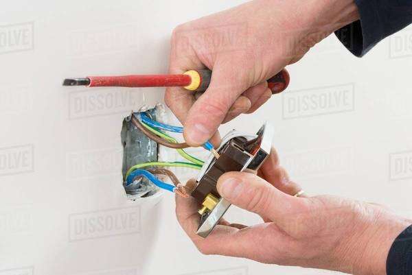 An electrician fixing a socket - Stock Photo - Dissolve