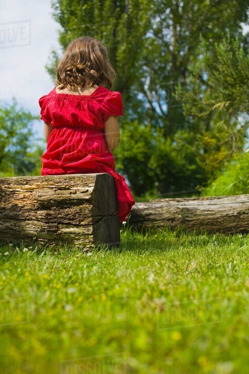 A girl sitting on a log - Royalty-free Stock Photo | Dissolve