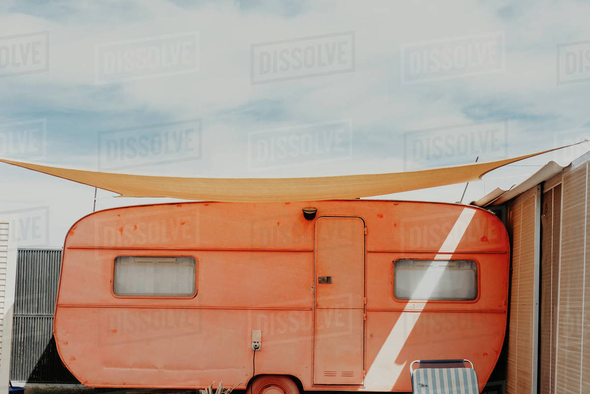 Exterior view of vintage orange camper van with sun-sail on ...