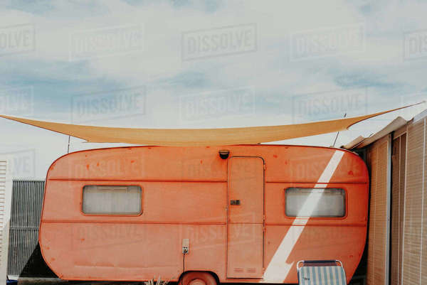 Exterior view of vintage orange camper van with sun-sail on ...