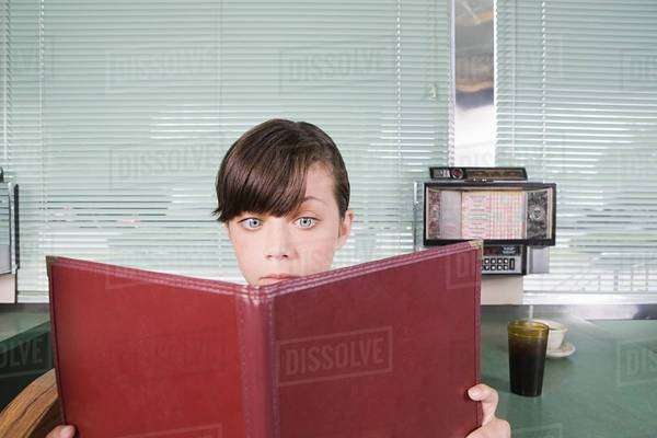 Girl reading a menu in a diner - Stock Photo - Dissolve