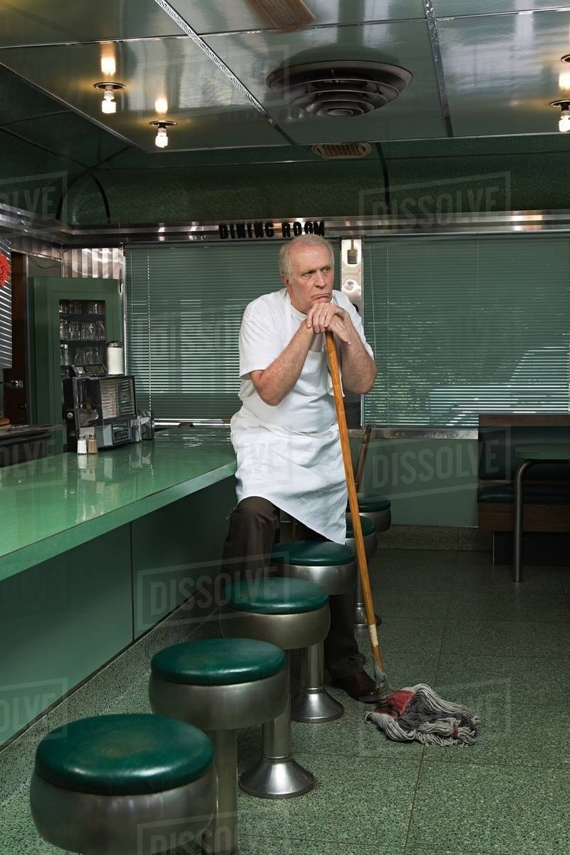 Diner cleaner leaning on his broom - Royalty-free Stock Photo | Dissolve