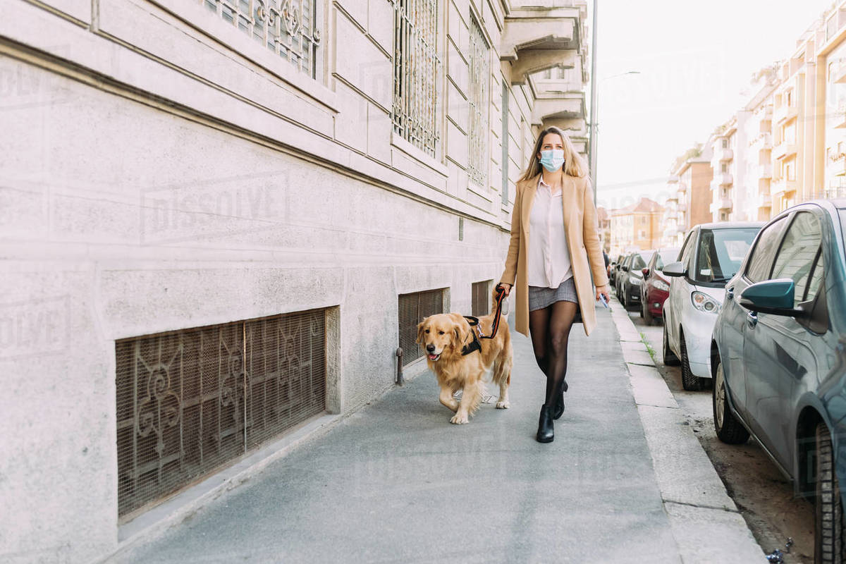 Italy, Young woman and dog walking along street - Stock Photo - Dissolve