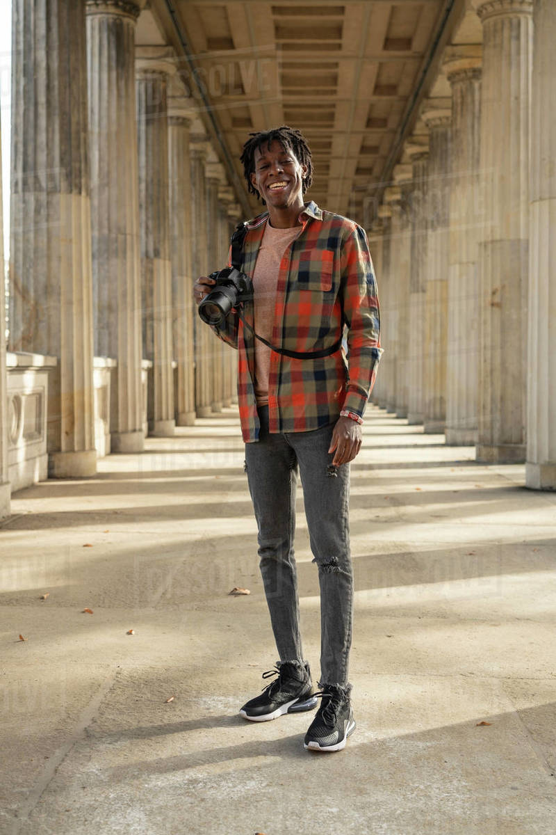 Germany, Berlin, Portrait of smiling man with camera - Royalty-free ...