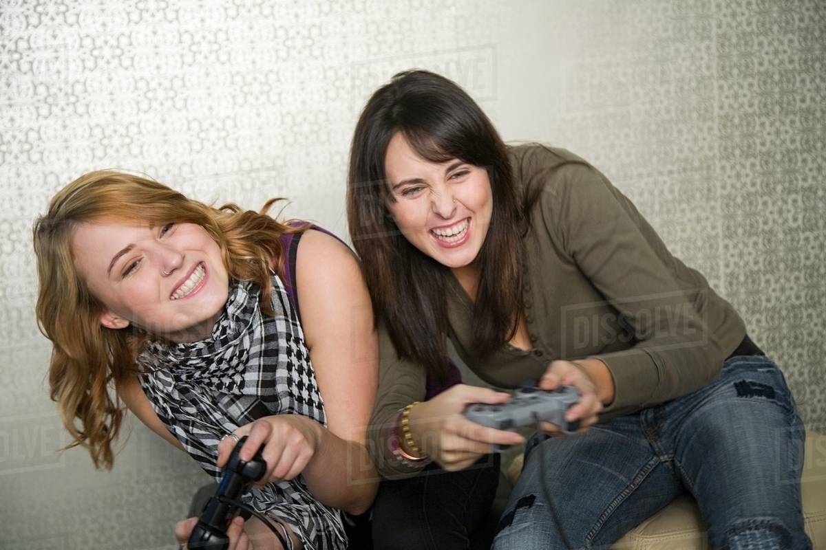 Teenage girls playing on games console - Stock Photo - Dissolve
