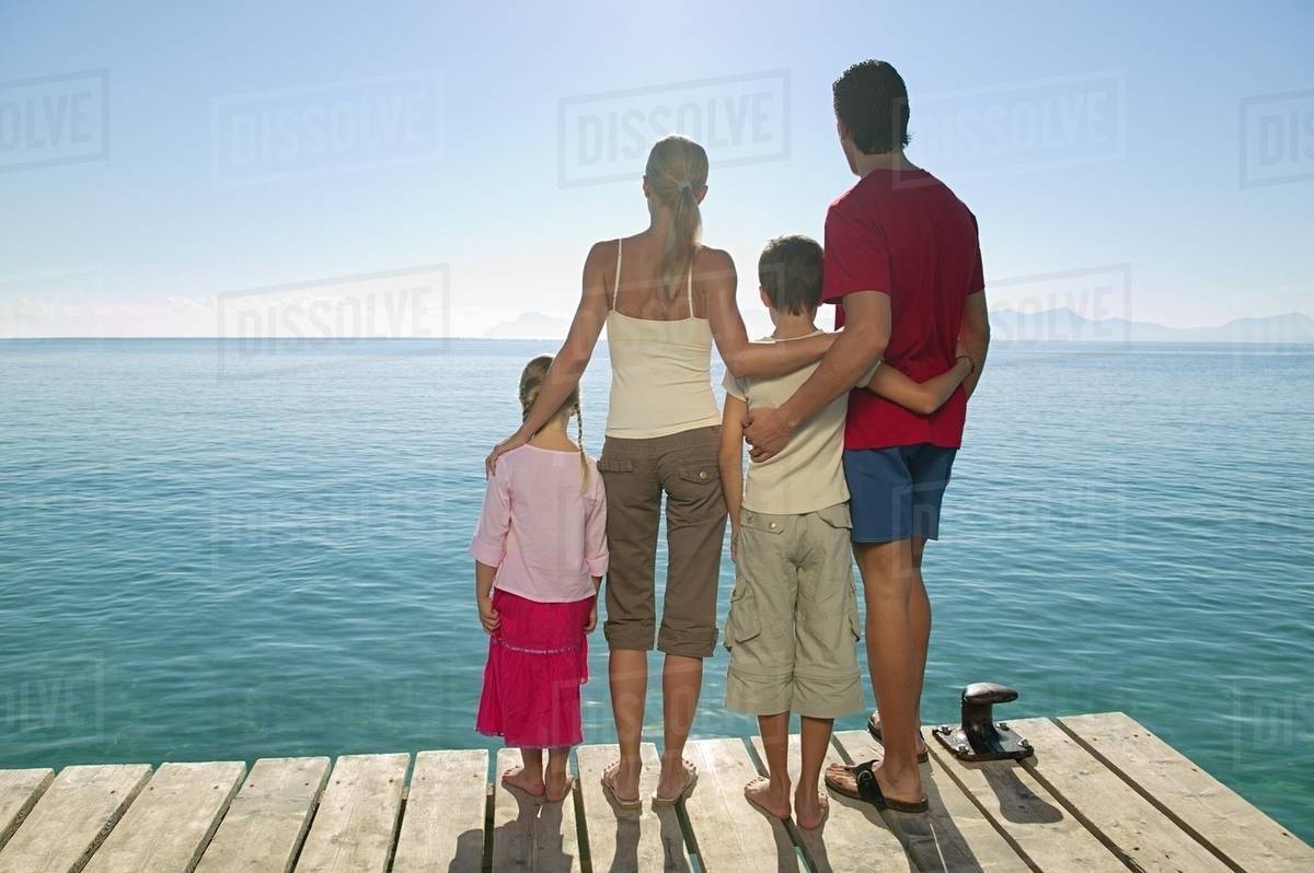 Rear view of family standing on jetty - Royalty-free Stock Photo | Dissolve