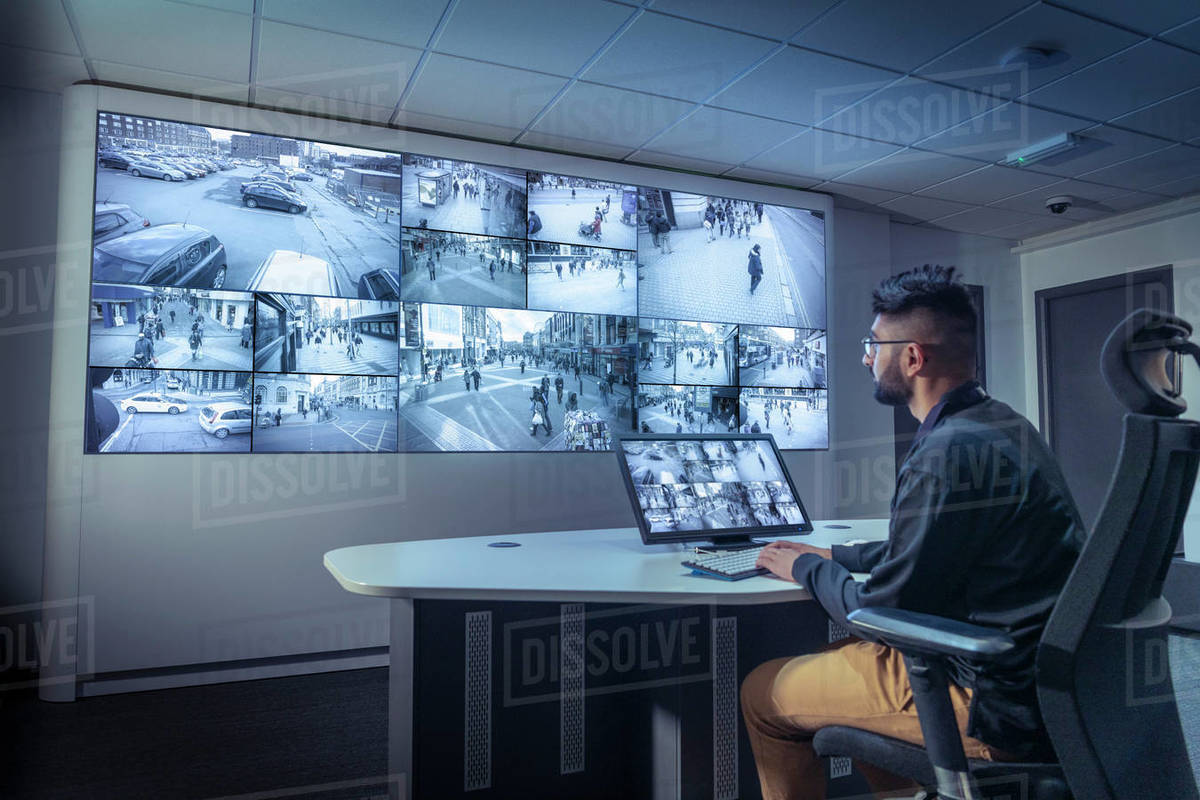 Operator looking at screens in CCTV control room - Stock Photo - Dissolve