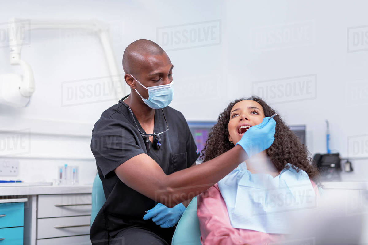 Dentist looking at patients teeth in dental surgery - Stock Photo ...