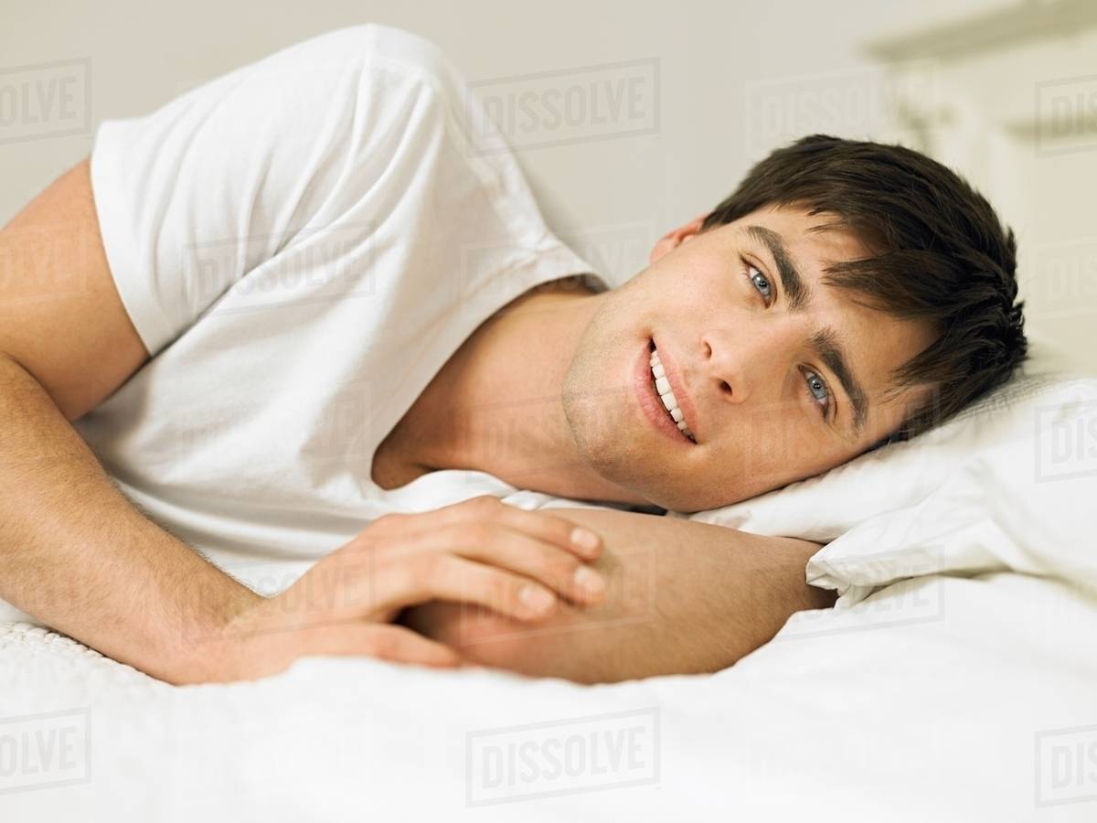 Young man lying on bed, portrait - Royalty-free Stock Photo | Dissolve