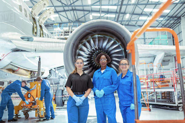 Portrait of female aircraft maintenance engineers in aircraft hangar ...
