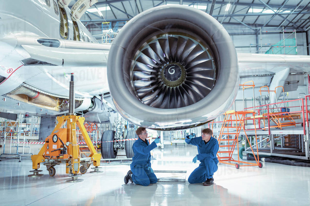 Apprentice aircraft maintenance engineers inspecting large jet engine ...