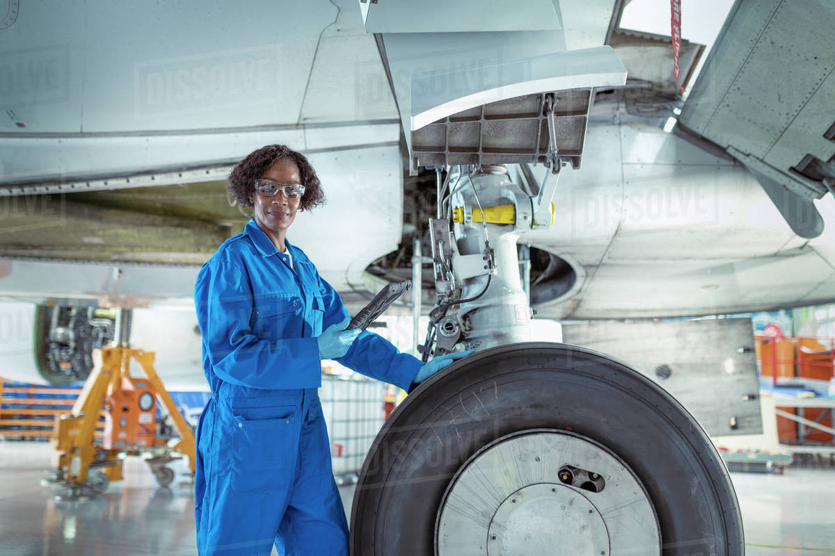 Female aircraft maintenance engineer underneath jet with digital tablet ...