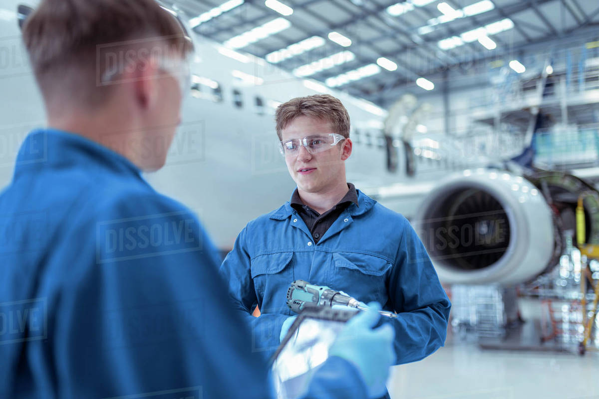 Apprentice aircraft maintenance engineers talking in aircraft ...
