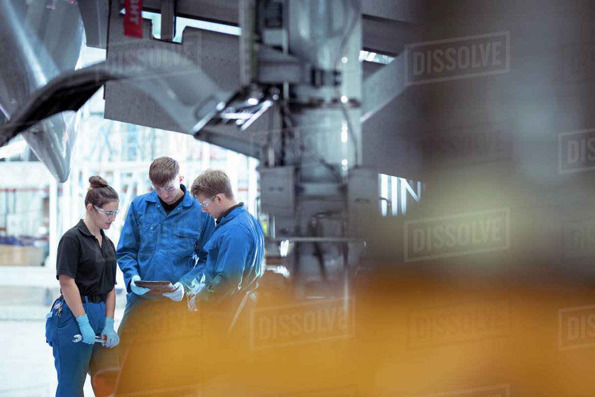 Team of apprentice aircraft maintenance engineers under large aircraft ...