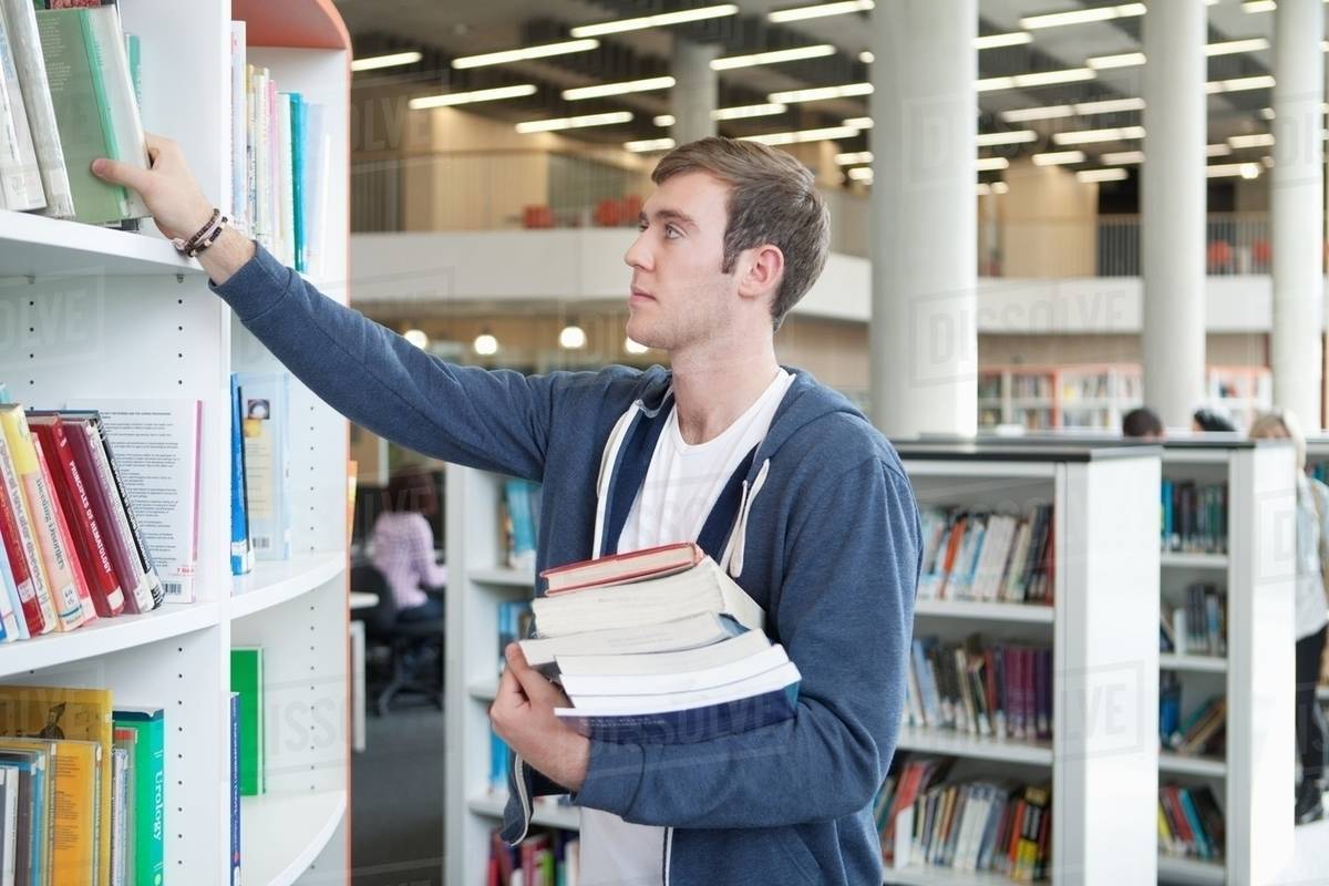 University student choosing textbooks in library - Stock Photo - Dissolve
