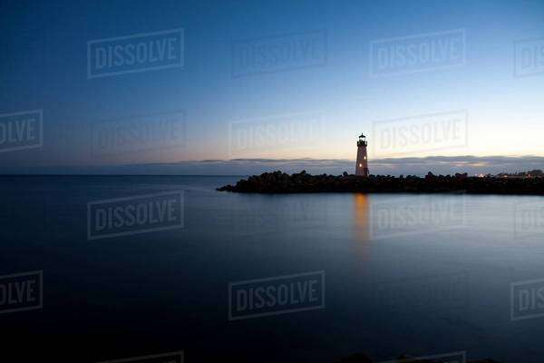 Lighthouse overlooking calm water at dusk - Royalty-free Stock Photo ...