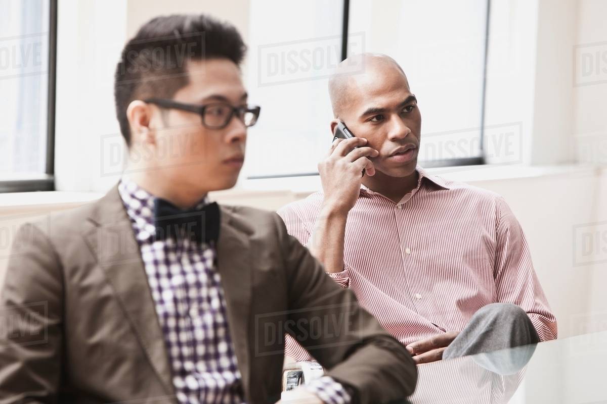 Two businessmen, one on the phone - Stock Photo - Dissolve