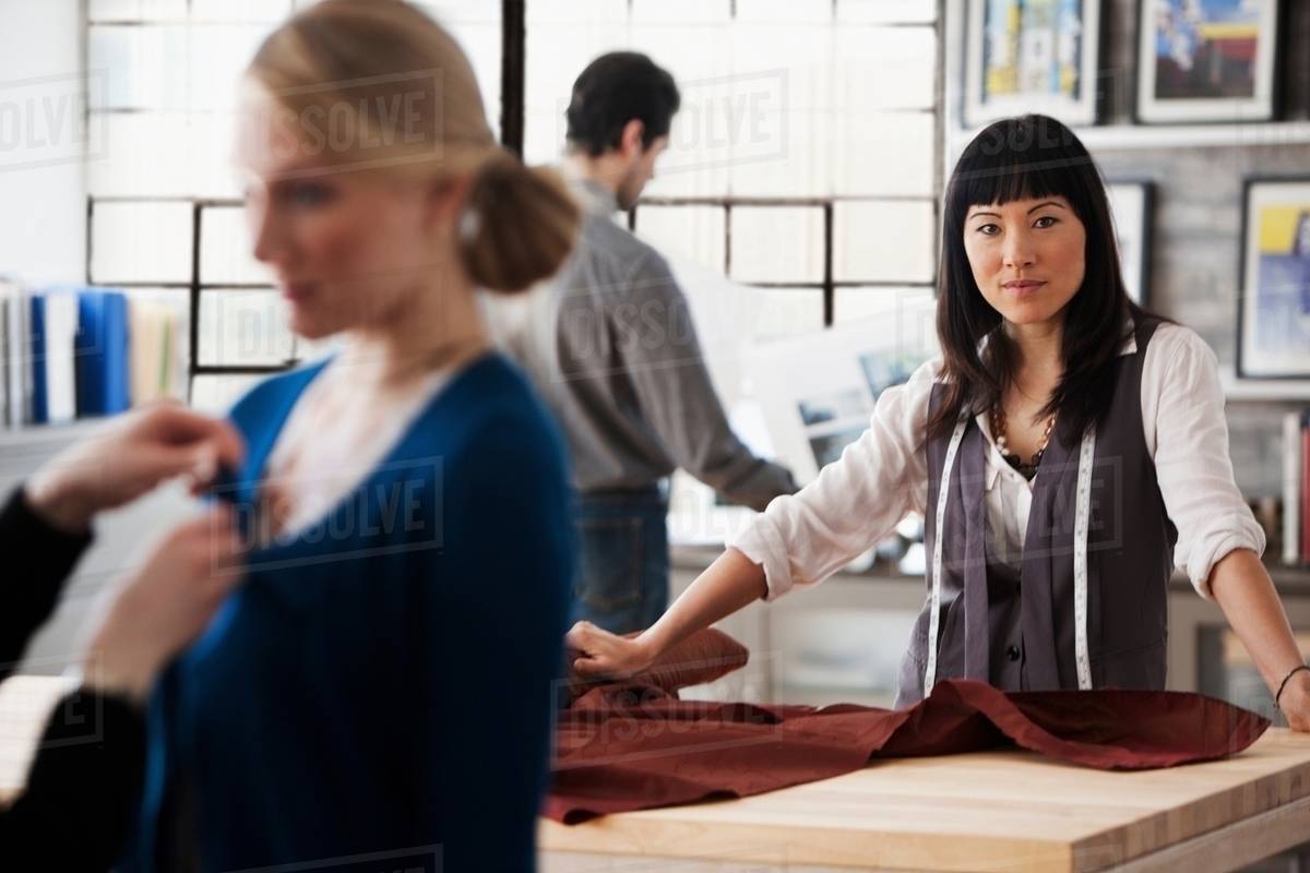 Portrait of fashion designer in busy studio - Stock Photo - Dissolve