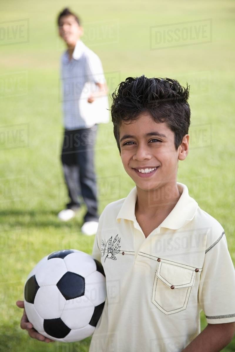 Portrait of a boy holding a football - Stock Photo - Dissolve
