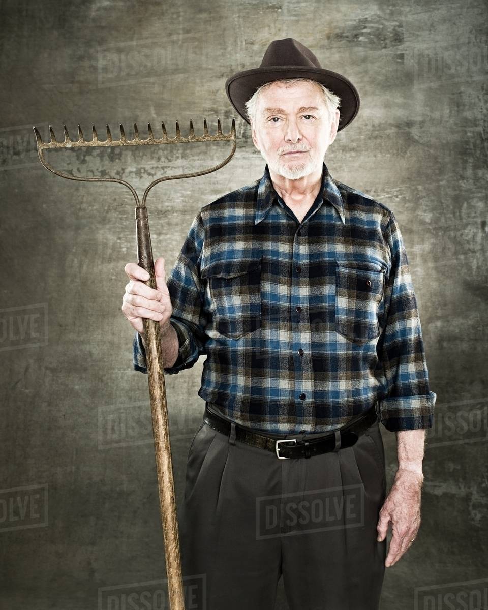 Portrait of a farmer holding a rake - Royalty-free Stock Photo | Dissolve
