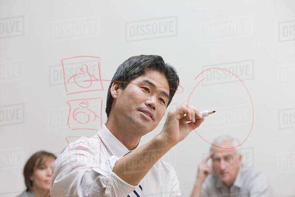 Man drawing diagram on glass wall - Royalty-free Stock Photo | Dissolve