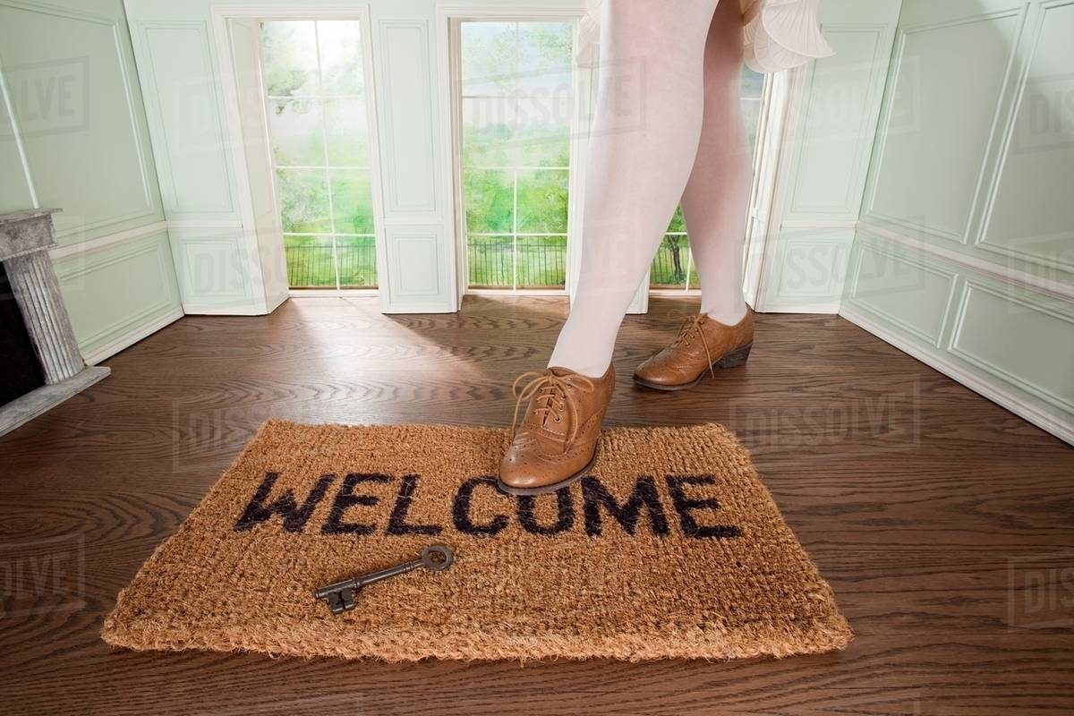 Legs of a woman and welcome mat with key in small room - Stock Photo ...