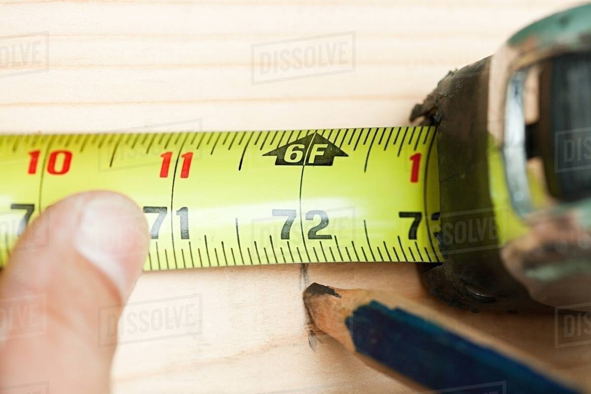 Woman measuring plank of wood and marking with pencil - Royalty-free ...