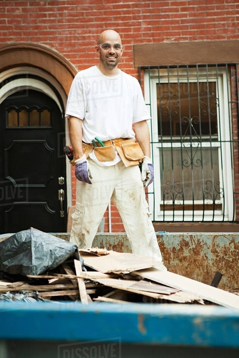 Man filling skip with rubble - Stock Photo - Dissolve