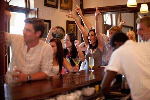 Group of young people cheering in bar - Stock Photo - Dissolve