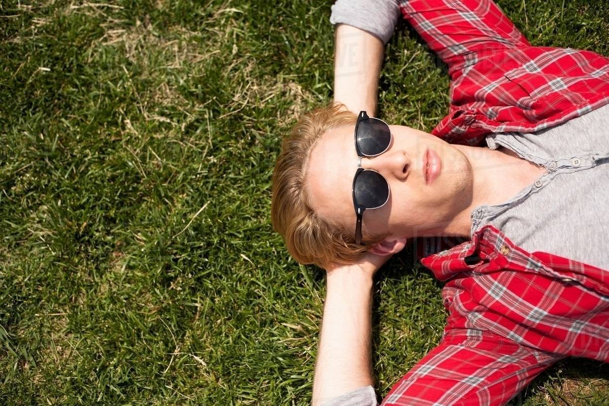 Young man lying down in park - Royalty-free Stock Photo | Dissolve