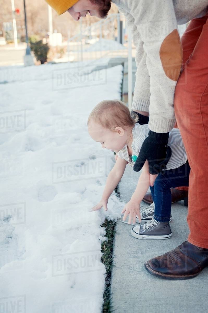 Young girl touching snow with father watching - Royalty-free Stock ...