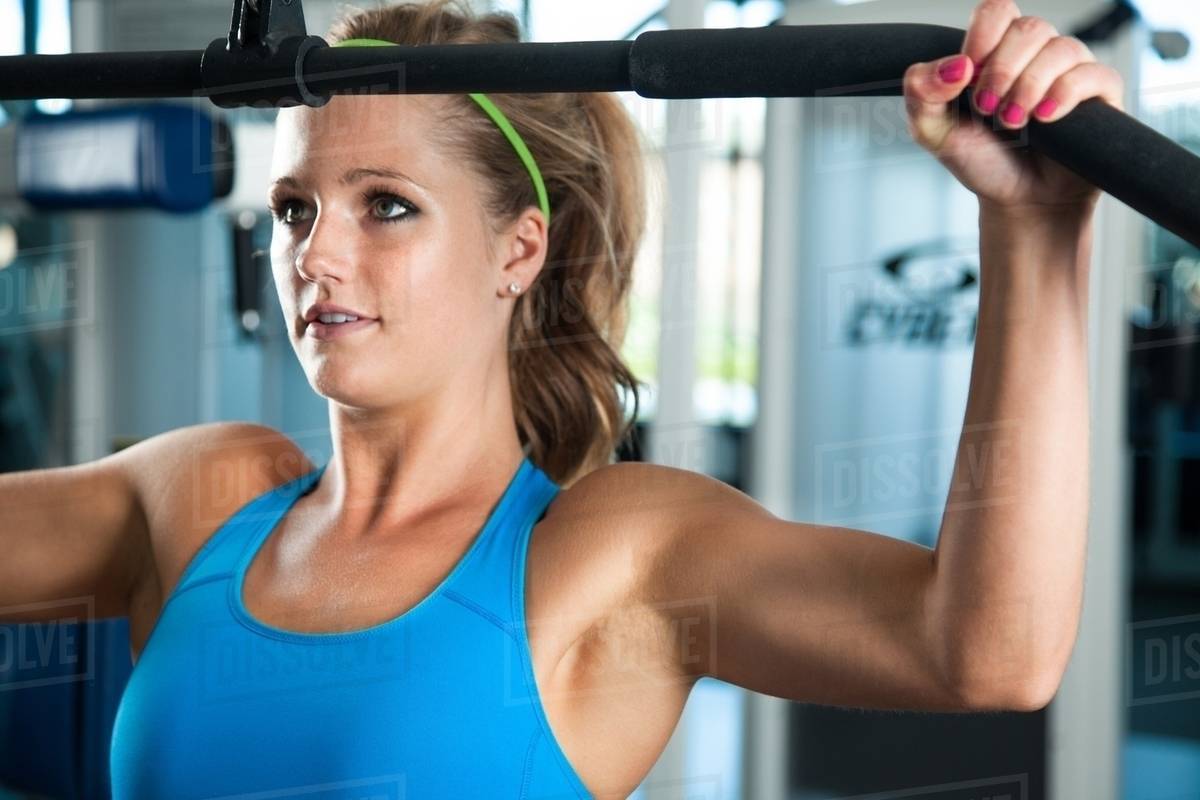 Close up of young woman pulling weights - Stock Photo - Dissolve