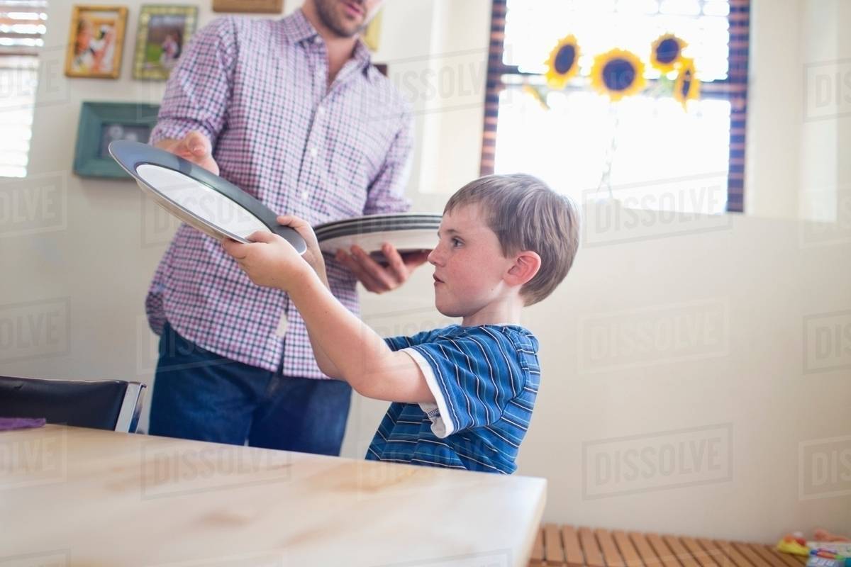 Son setting the table with father - Stock Photo - Dissolve