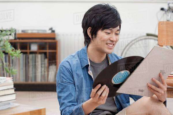 Portrait of young man holding vinyl record - Stock Photo - Dissolve