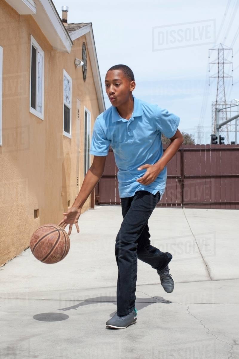 Boy bouncing basketball in yard - Stock Photo - Dissolve