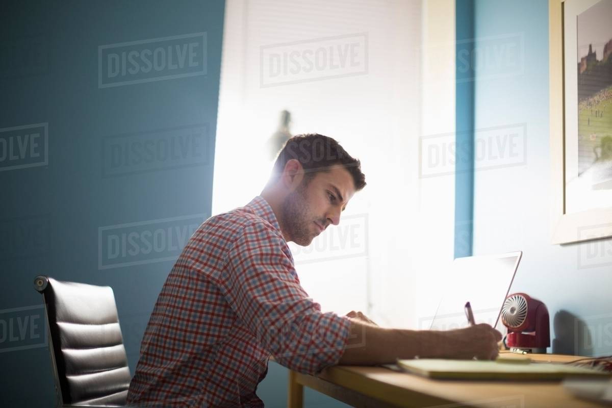 Man sitting at desk writing - Stock Photo - Dissolve