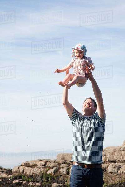 Father throwing child in air on beach - Stock Photo - Dissolve