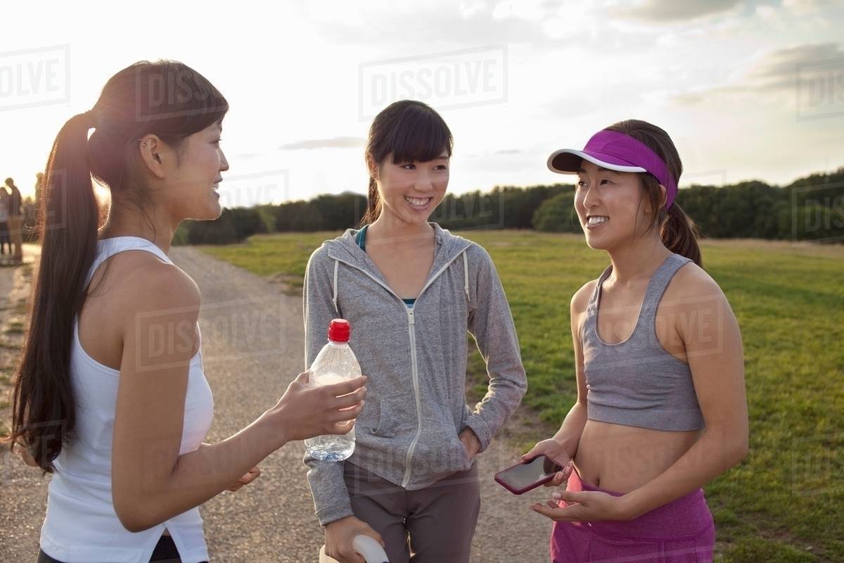 Three young female runners chatting after run - Stock Photo - Dissolve
