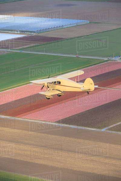 Bi-plane flying above flower fields - Stock Photo - Dissolve