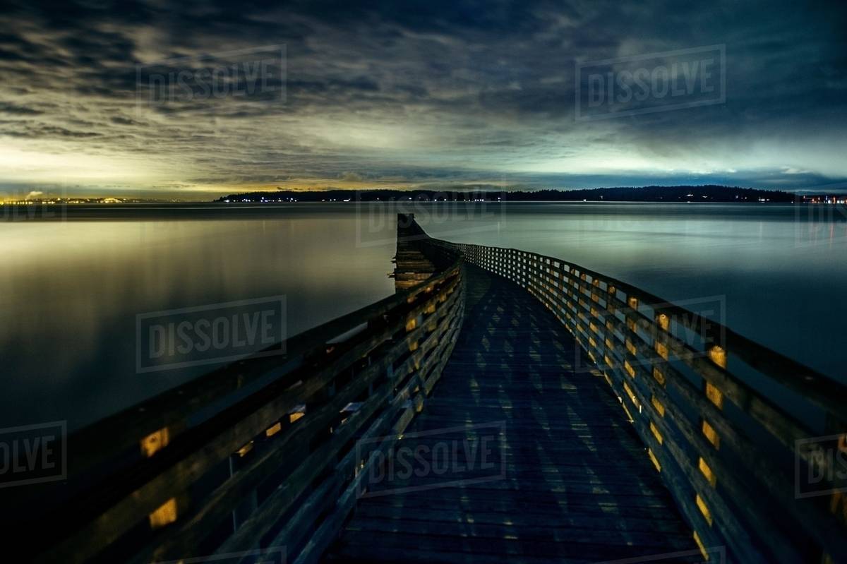 Silhouetted view of winding wooden pier over Puget Sound at dawn ...