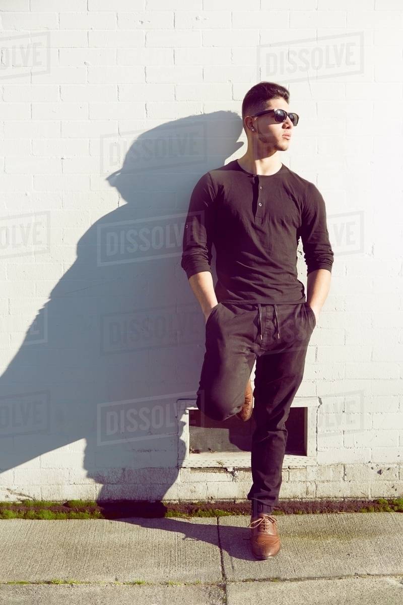 Young man standing by white wall - Royalty-free Stock Photo | Dissolve