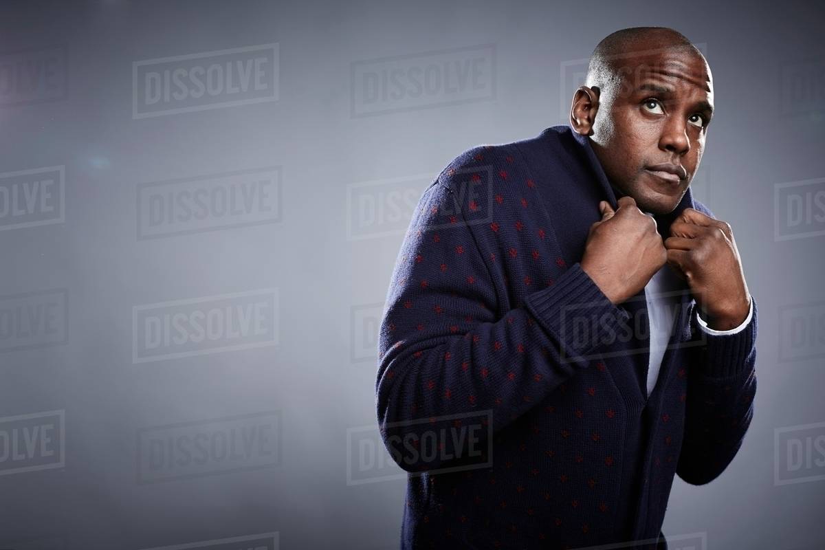 Portrait of young man pulling collar around him - Stock Photo - Dissolve
