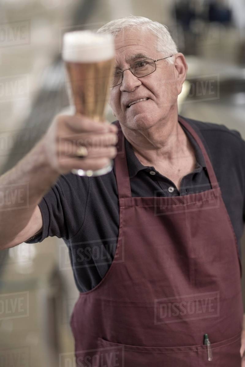 Brewer in brewery holding up a glass of beer - Royalty-free Stock Photo ...