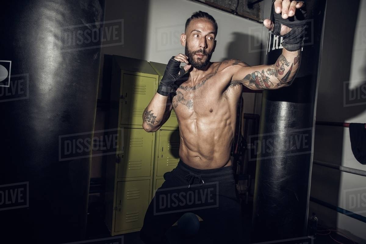 Poised male boxer with bandaged hands in gym - Stock Photo - Dissolve